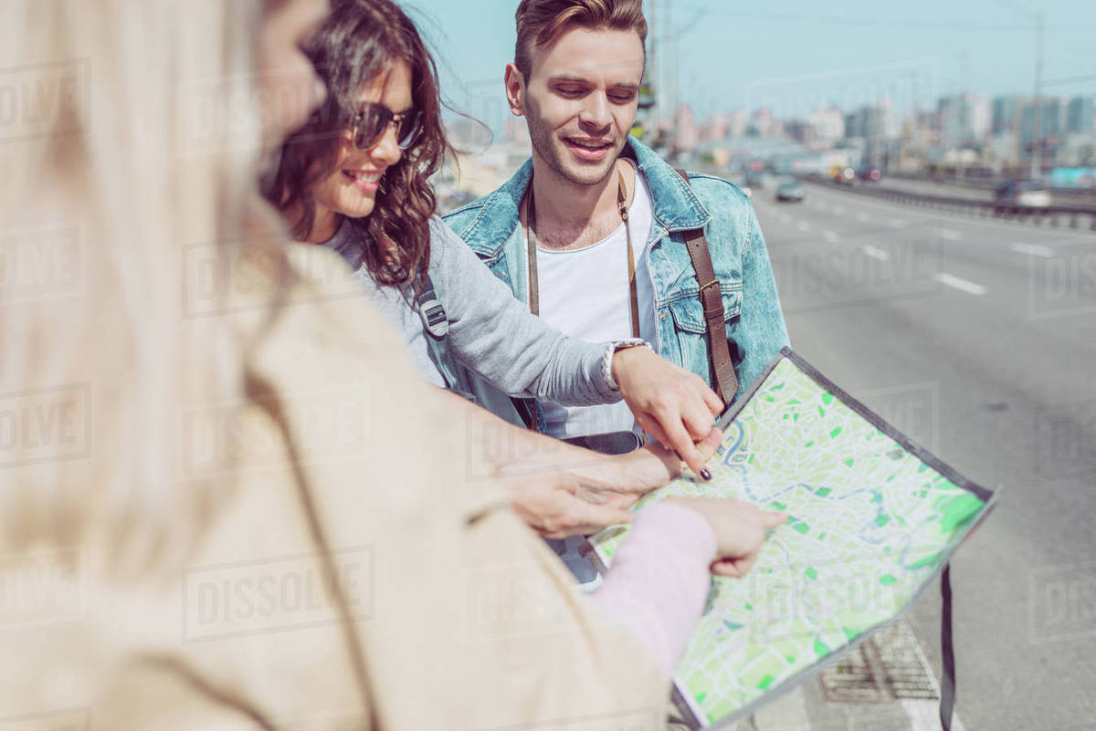 Partial view of tourists looking for destination on map during trip ...