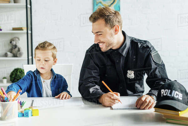 Happy young father in police uniform and his little son drawing ...