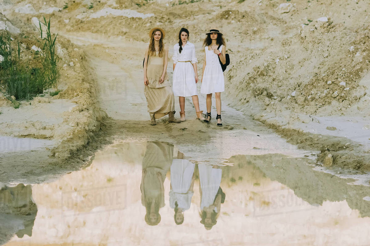 Elegant stylish girls posing near big puddle in sandy canyon - Royalty ...