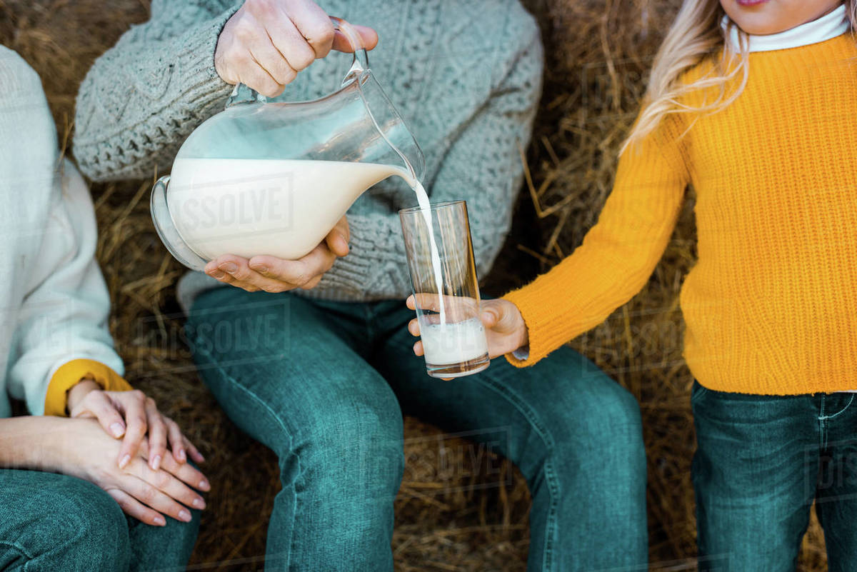 Partial view of man pouring milk to little daughter while his wife ...