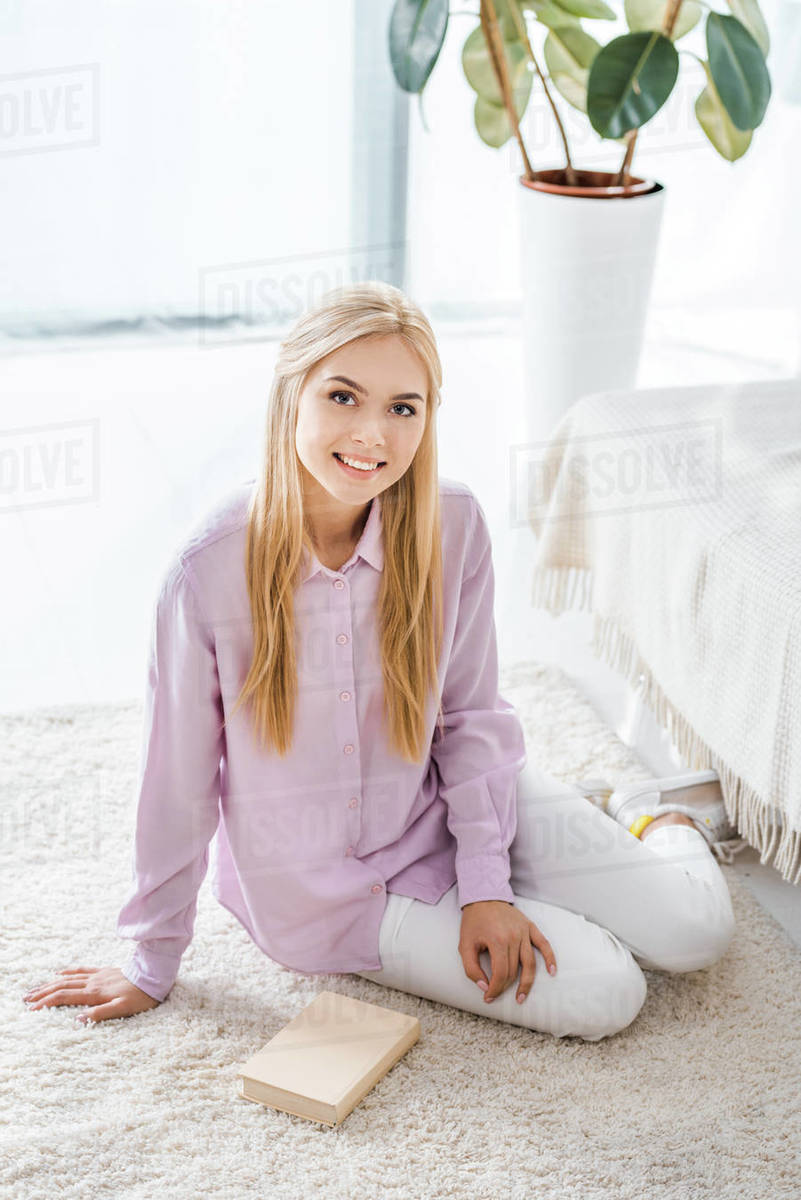 Young beautiful woman sitting on carpet with book at home - Stock Photo ...