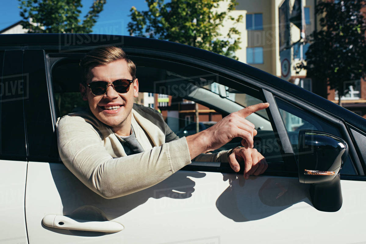 Young man leaning out car window of driving automobile - Stock Photo ...