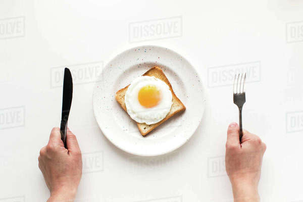 Cropped view of person eating breakfast with fried egg on toast ...
