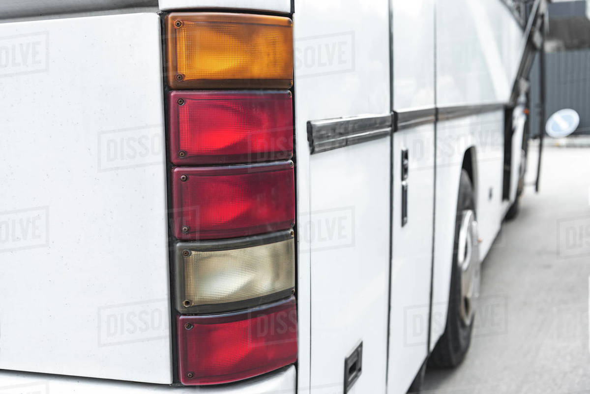 Selective focus of white travel bus headlights at urban street ...