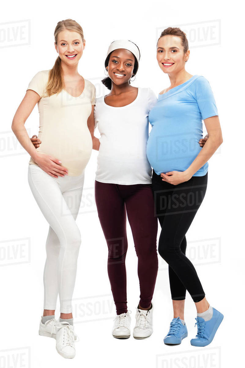 Full length of three pregnant women standing and hugging isolated on ...