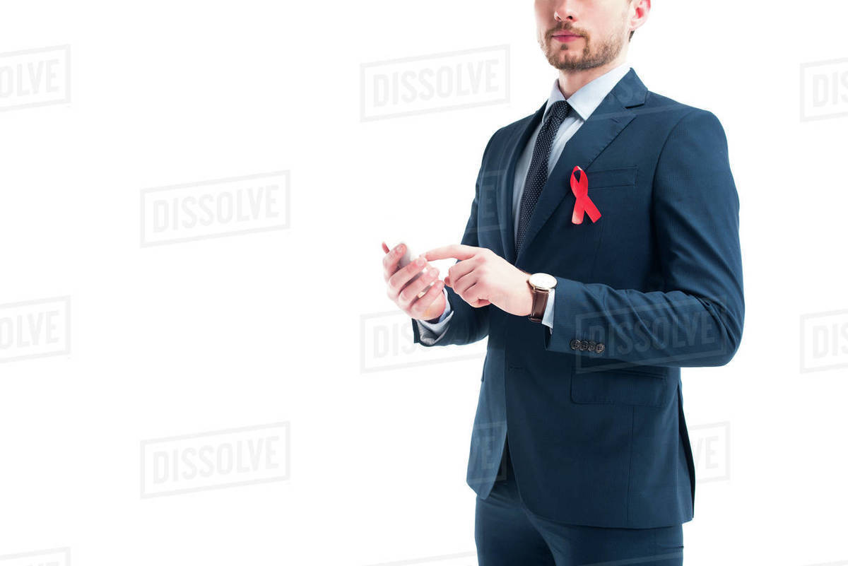 Cropped image of businessman with red ribbon on suit using smartphone ...