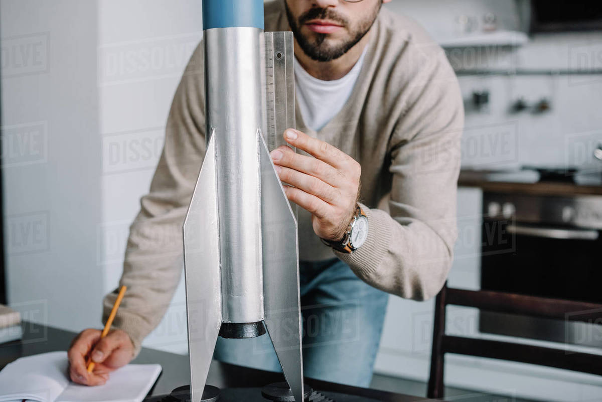 Cropped image of engineer modeling rocket and measuring with ruler at ...