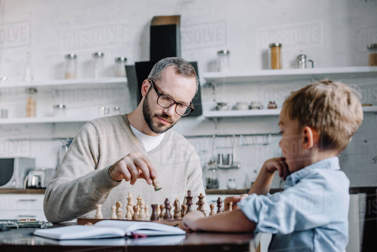 Father and adorable little son playing chess together at home - Royalty ...