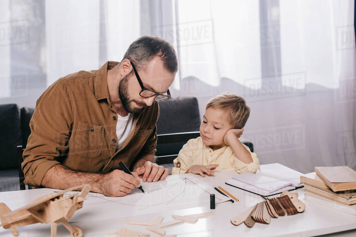Focused father and son modeling wooden plane at home - Stock Photo ...