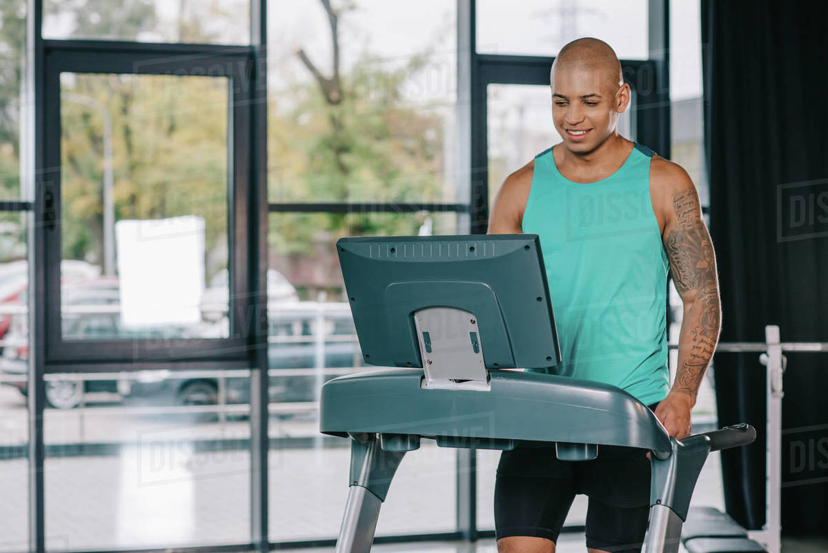 Smiling African American male athlete on treadmill at gym - Royalty ...