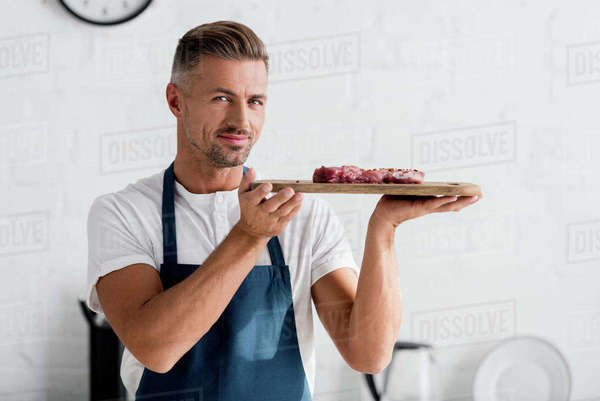 Adult smiling man holding steak on cutting board - Royalty-free Stock ...