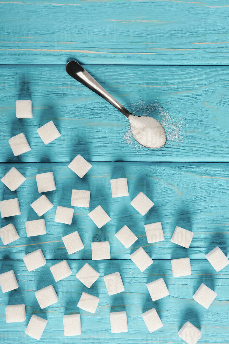top view of powdered and refined sugar on wooden turquoise tabletop ...