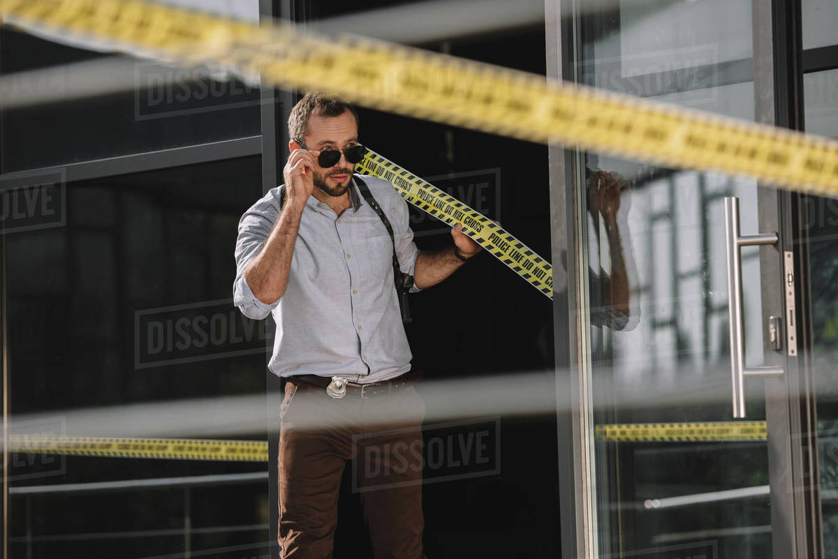 Male detective straightening sunglasses holding on the cross line ...