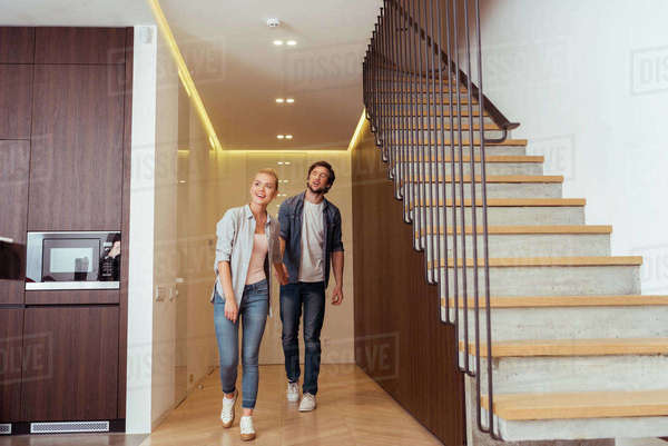 Smiling family couple holding hands near stairs at home - Royalty-free ...