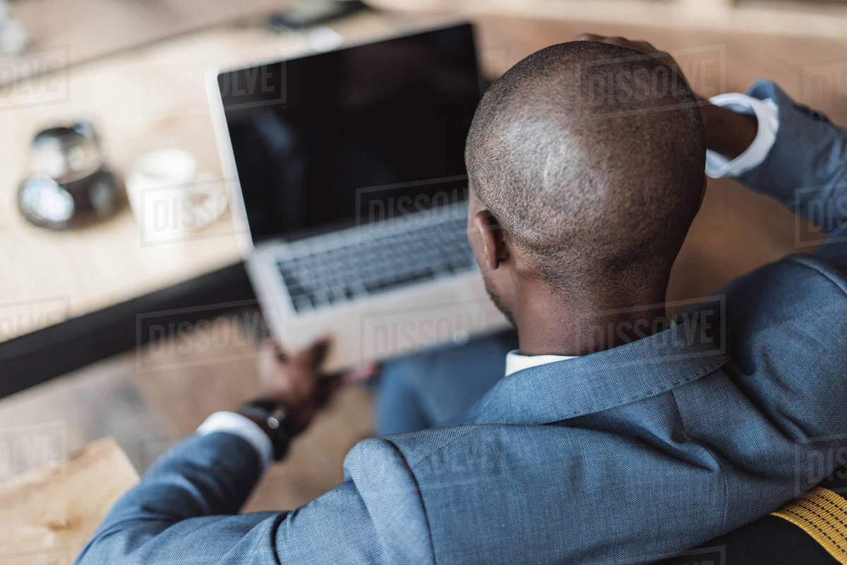 back view of african american businessman working with laptop in cafe ...