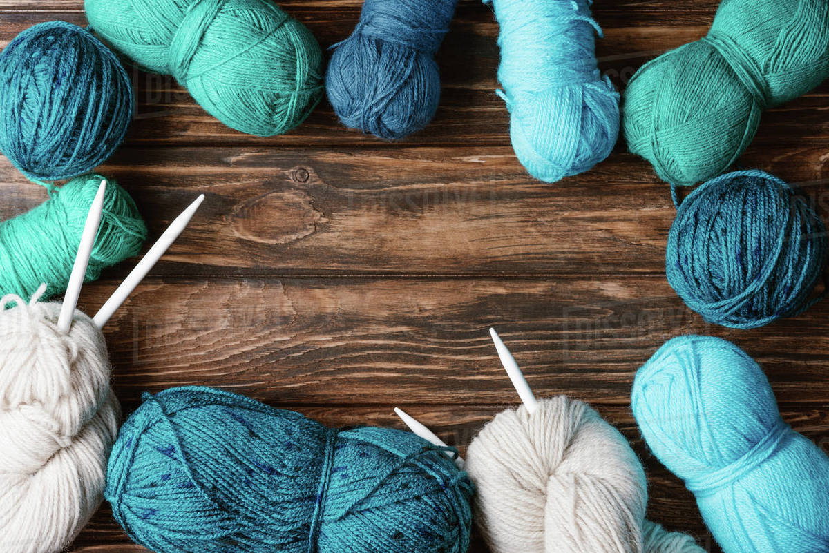 flat lay with arranged yarn clews and knitting needles on wooden ...