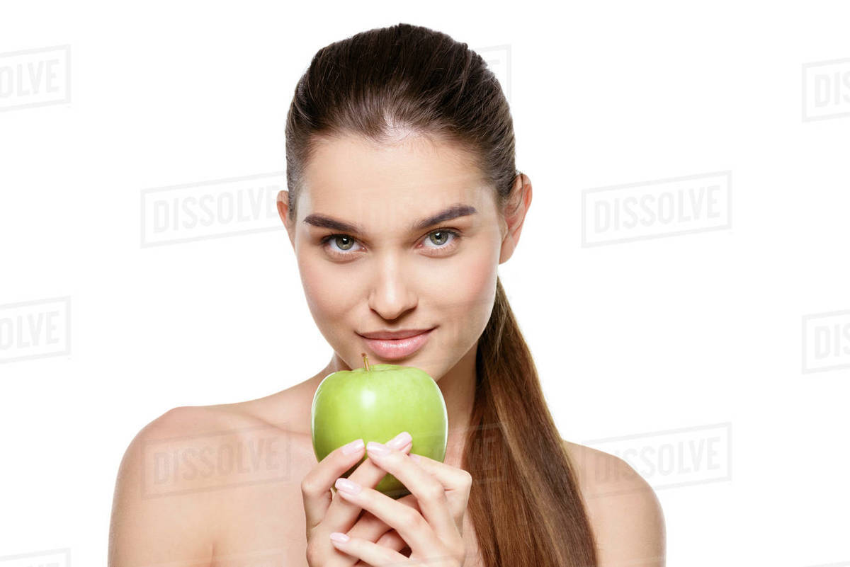 Beautiful young woman holding green apple and posing at camera isolated ...