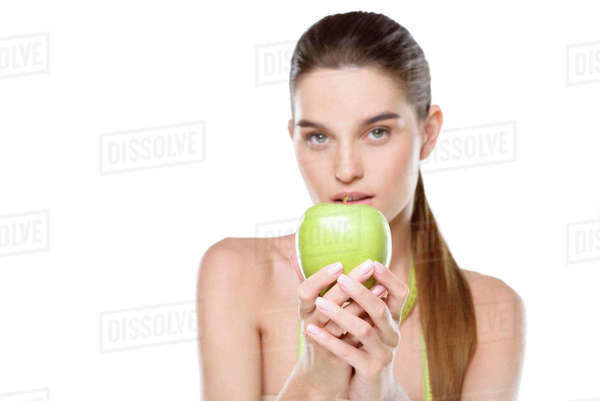 Beautiful young woman holding green apple and posing at camera isolated ...