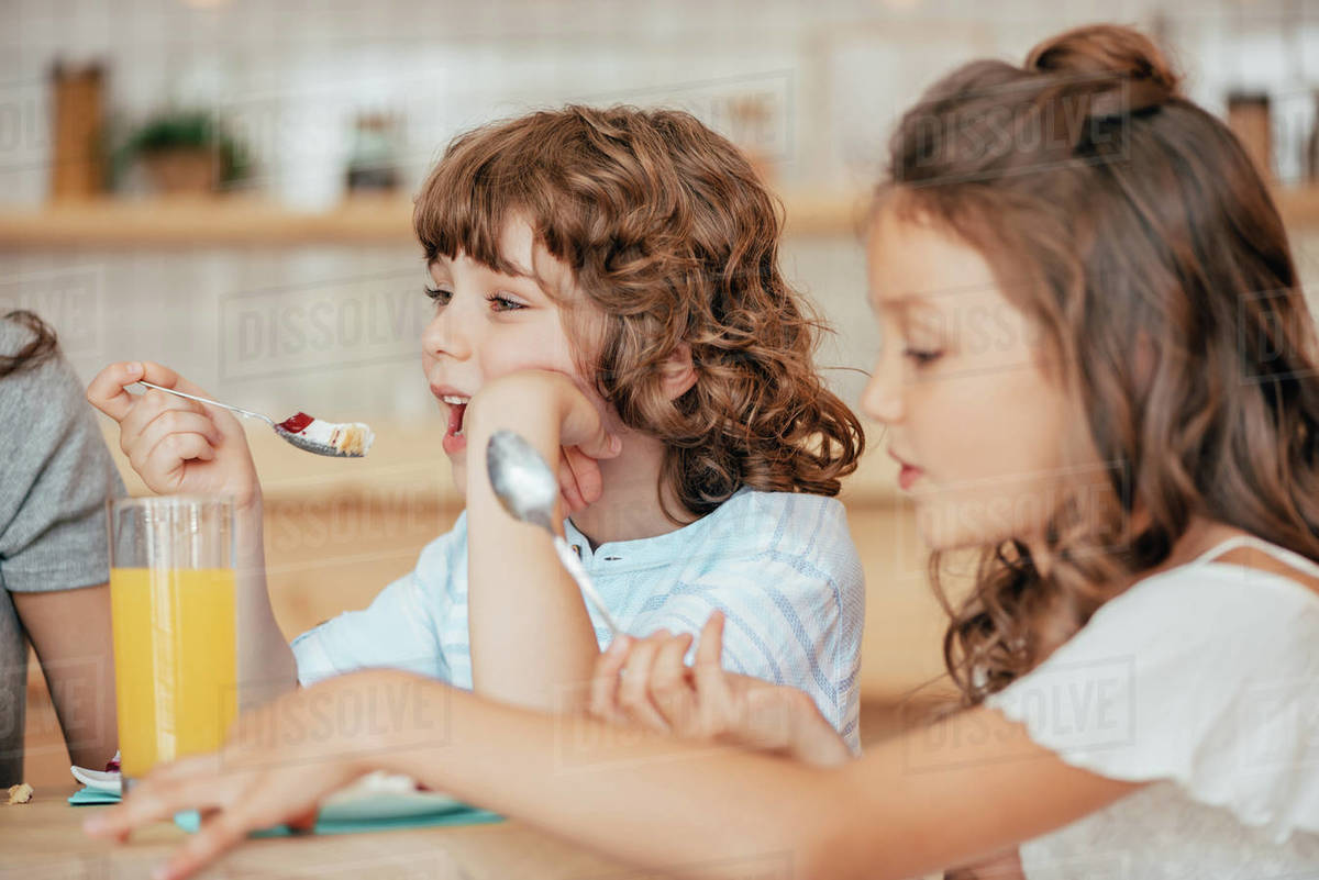 portrait of little kids eating desserts in cafe with orange juice ...
