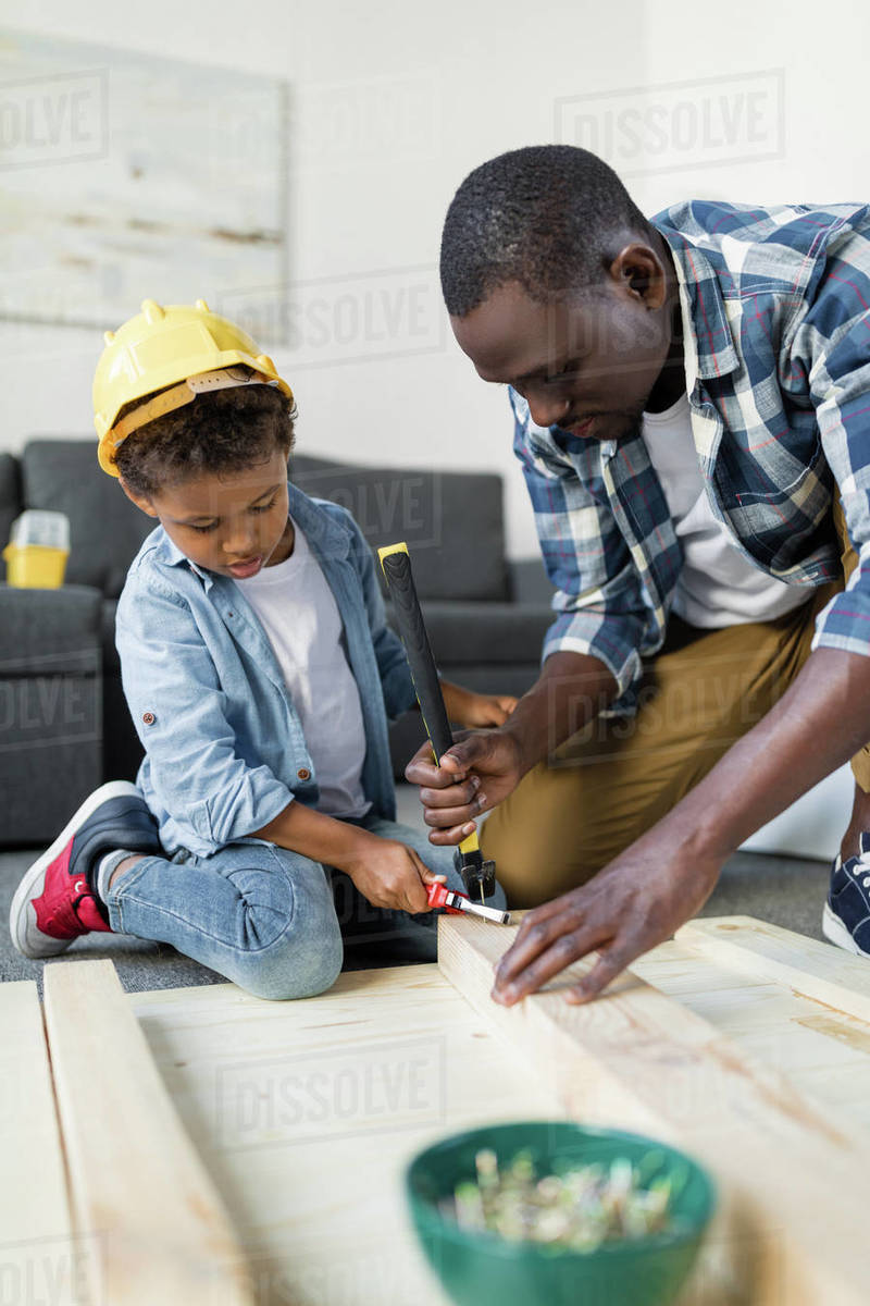 Adorable African American father and son constructing table - Royalty ...