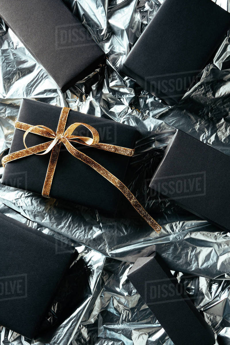 Flat lay with arranged gift with golden ribbon and blank black boxes on ...