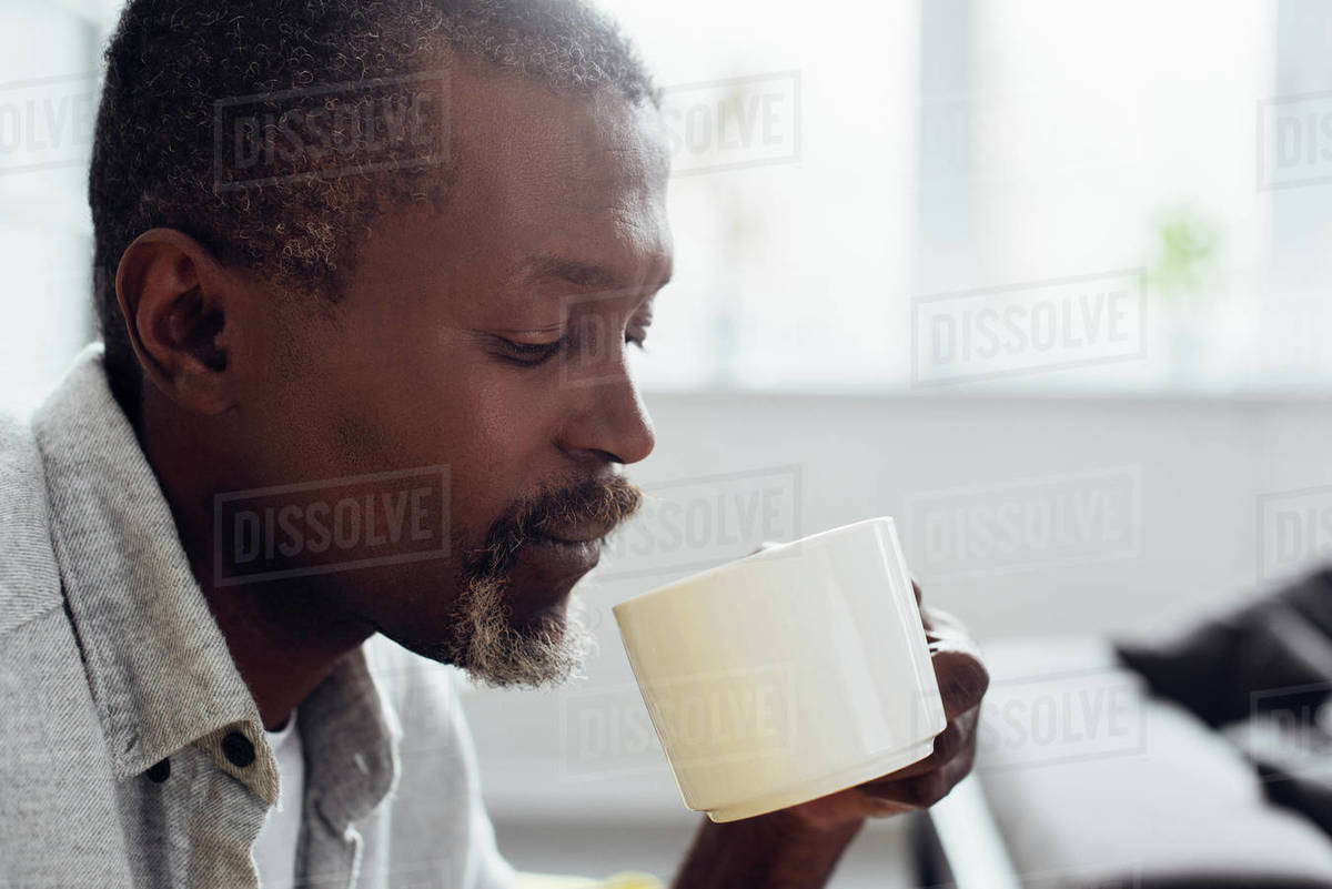 Close up of mature african american man drinking coffee in living room ...