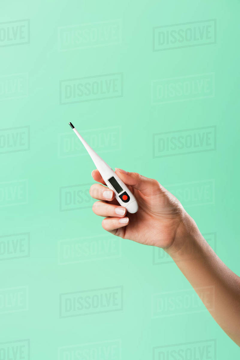 Cropped shot of person holding electronic thermometer isolated on green ...