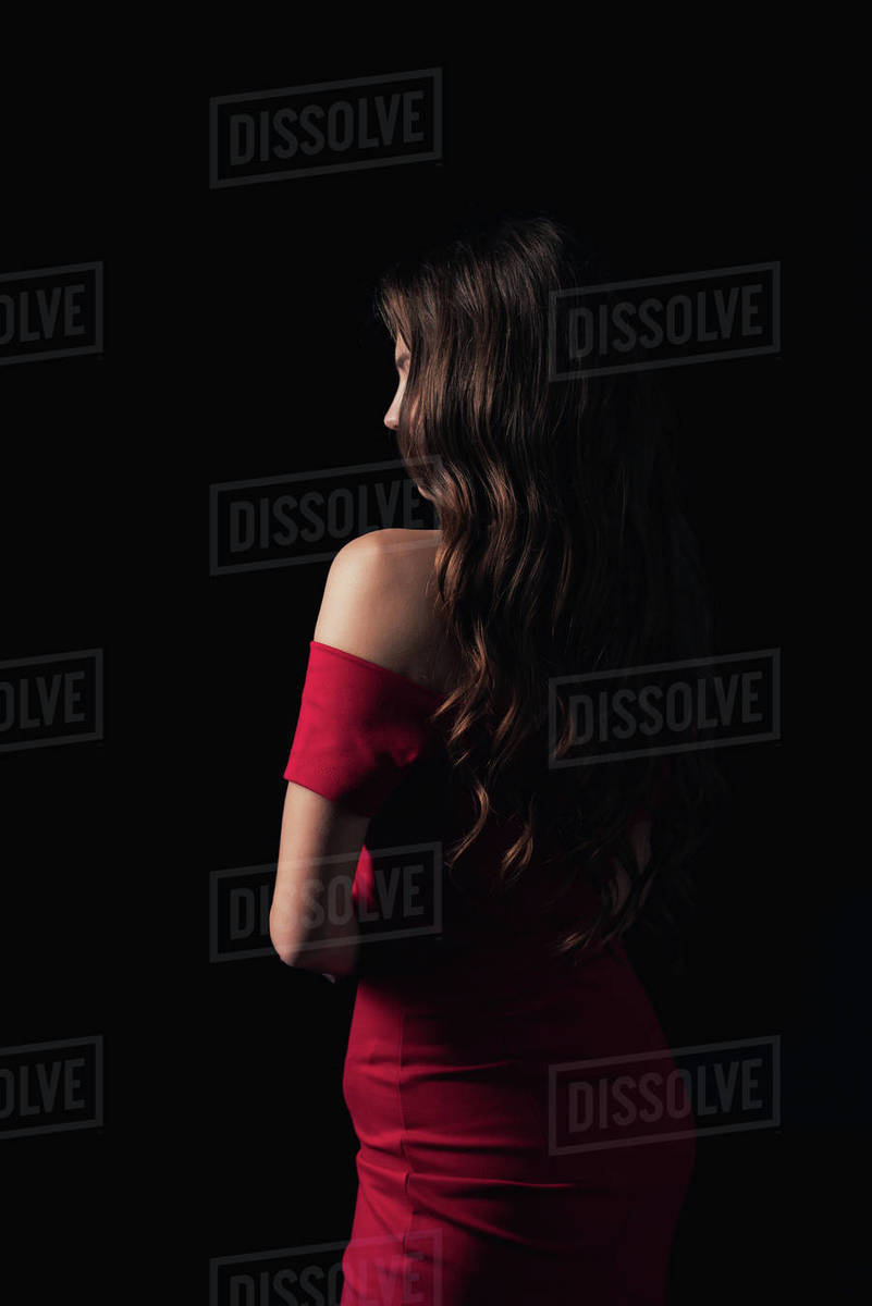 Back view of woman in red dress posing isolated on black - Royalty-free ...