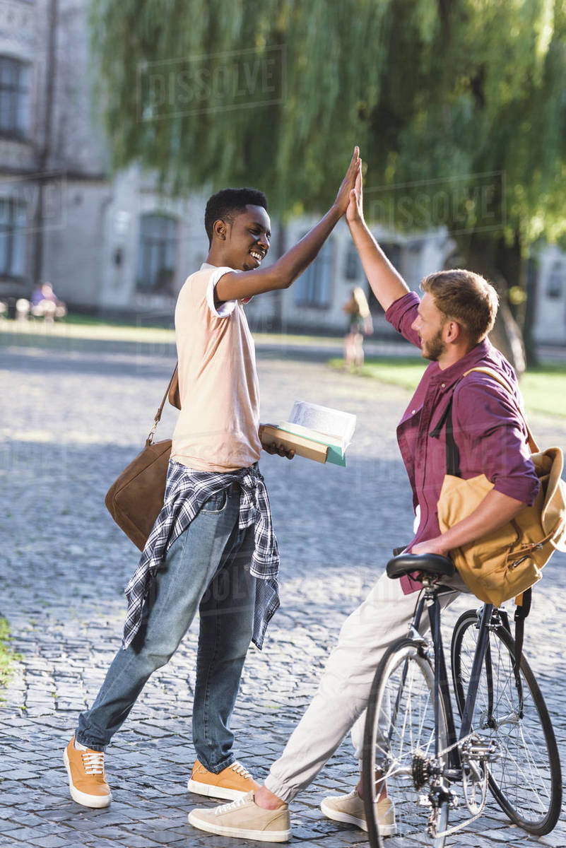 Young students making high five in park - Stock Photo - Dissolve