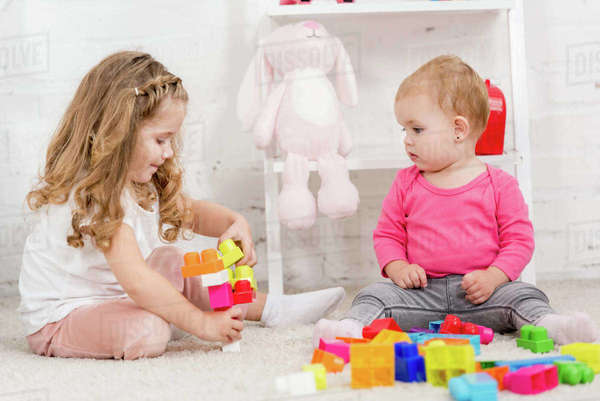Adorable sisters playing with constructor together on carpet in ...