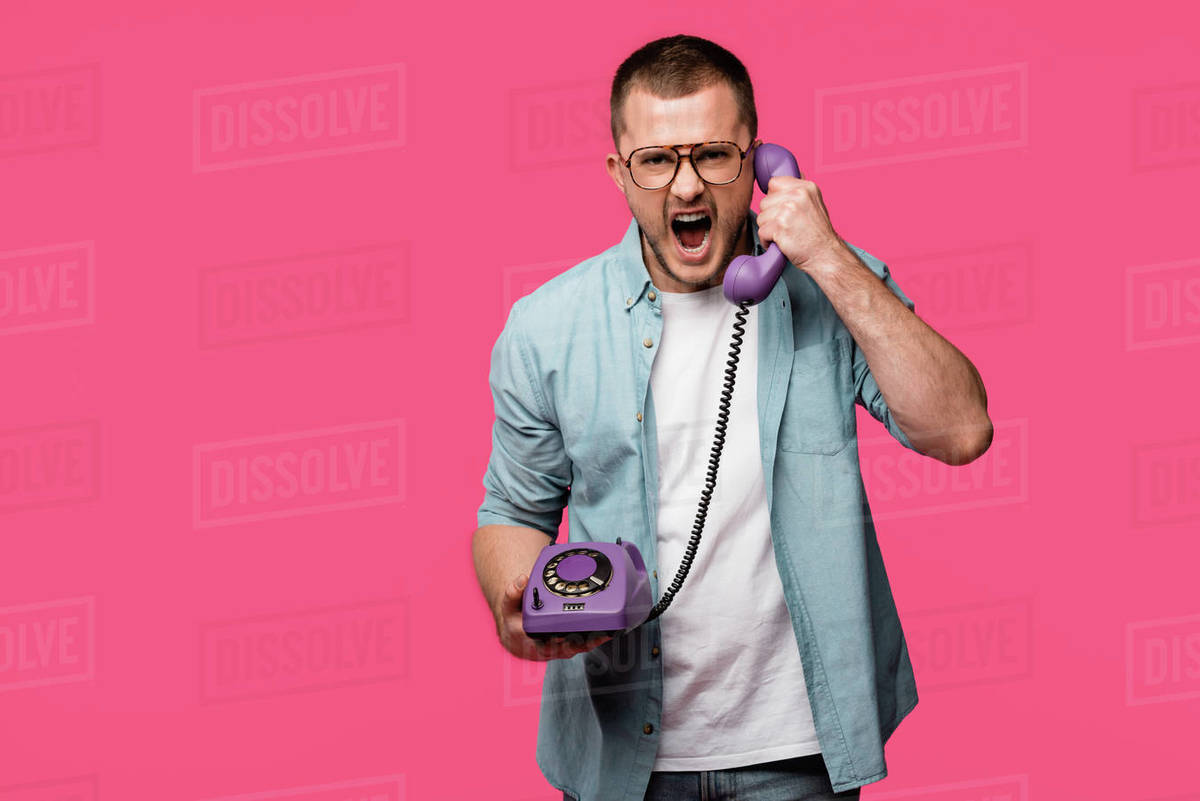 emotional young man yelling at handset and looking at camera isolated ...