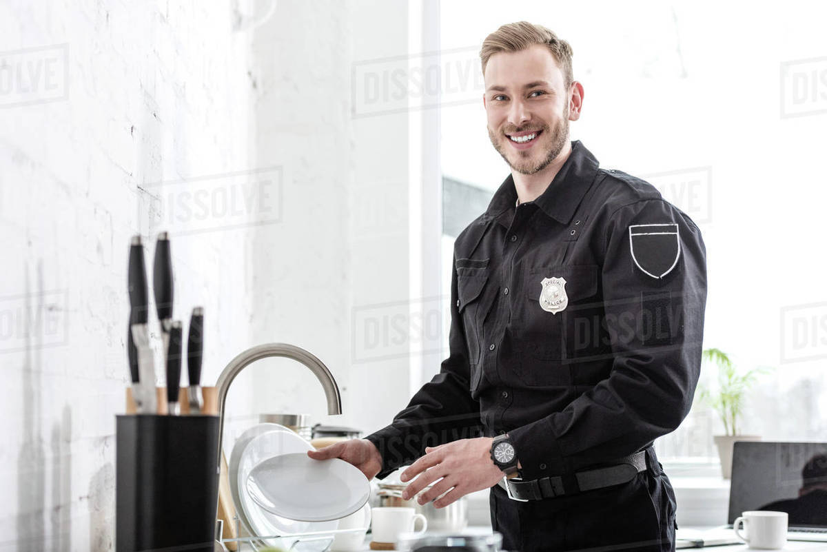 Handsome police officer washing dishes at kitchen - Royalty-free Stock ...