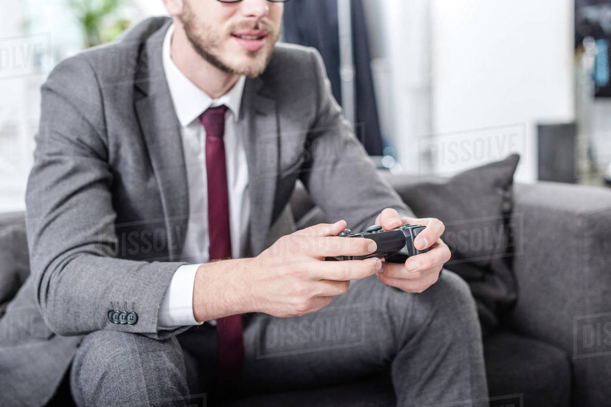 cropped view of businessman holding console and playing video game at ...