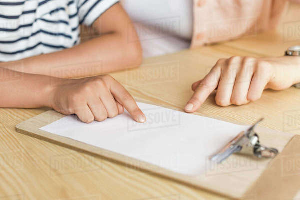 Cropped shot of woman and boy pointing at blank paper on clipboard ...