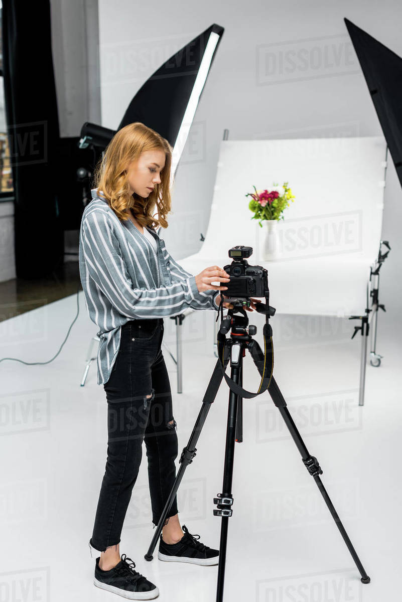 Beautiful young female photographer shooting flowers in photo studio ...