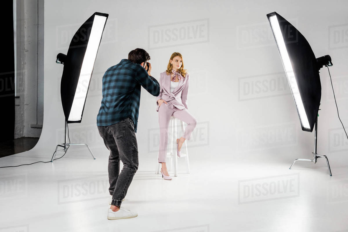 Back view of photographer shooting beautiful young female model in ...