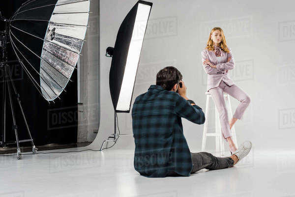 Back view of photographer sitting and shooting beautiful female model ...
