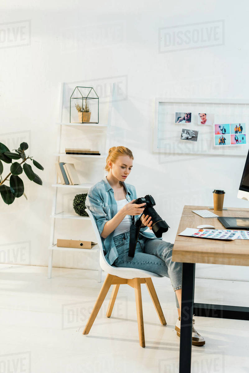 Beautiful young female photographer using camera at workplace - Stock ...