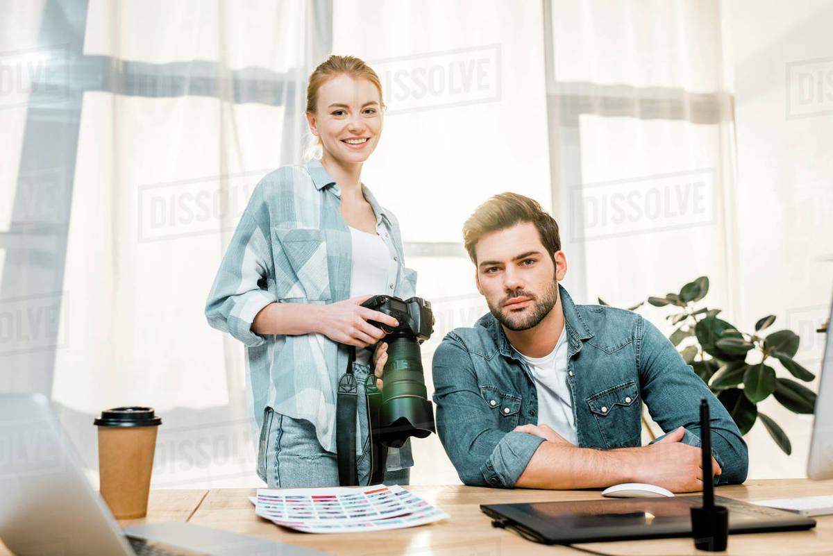 Professional young photographers working together and smiling at camera ...