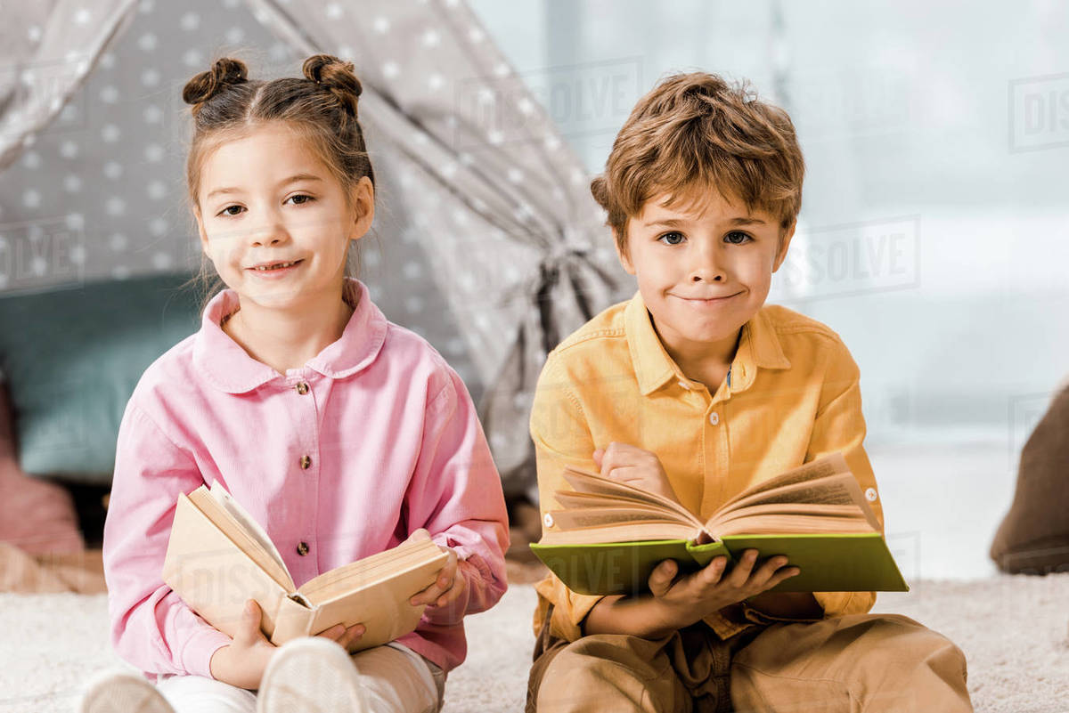 Beautiful children holding books and smiling at camera together ...
