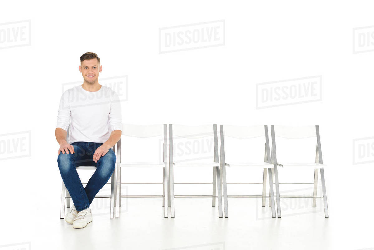 Cheerful smiling man sitting alone isolated on white - Stock Photo ...