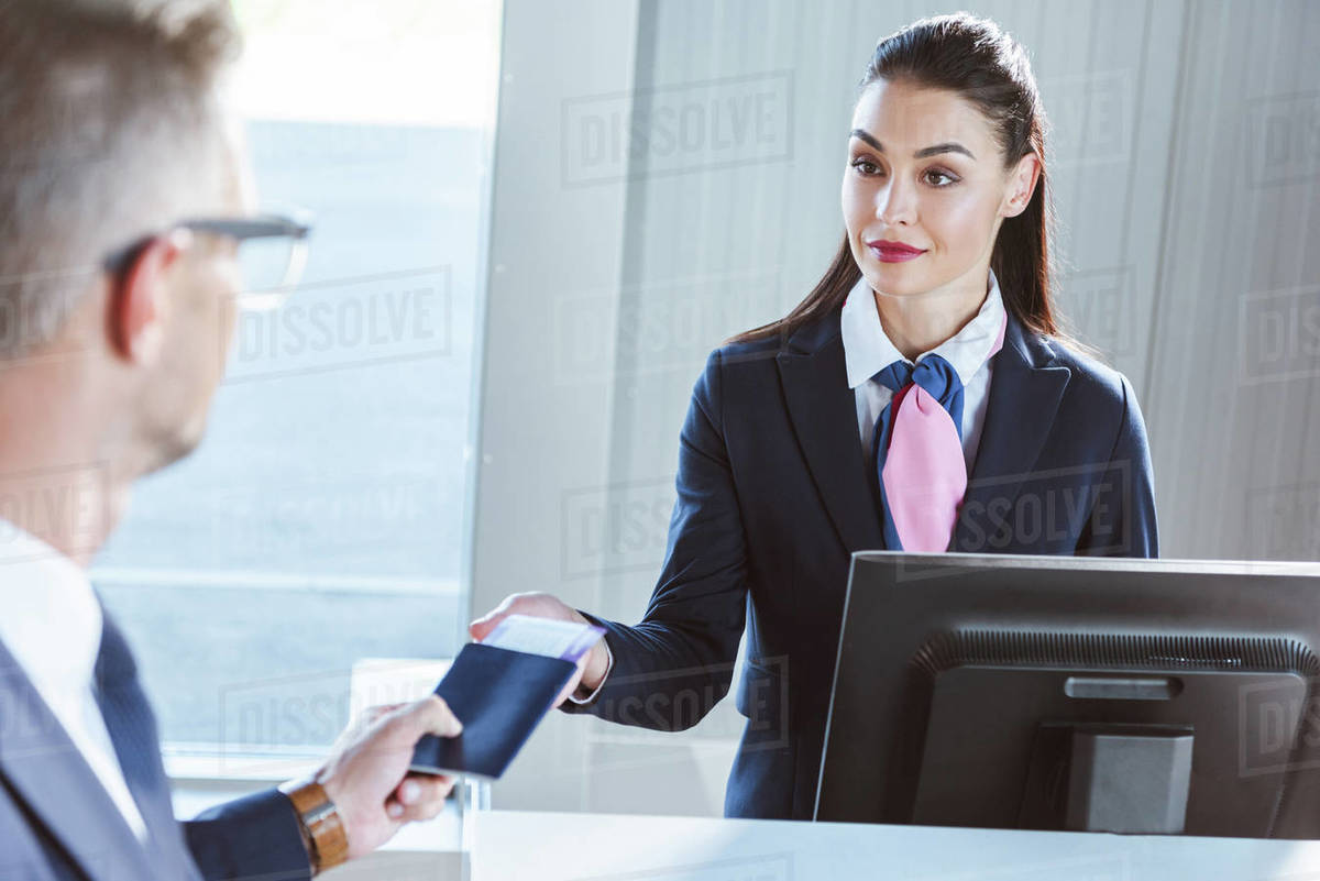 Businessman giving documents to female airport worker at check-in in ...