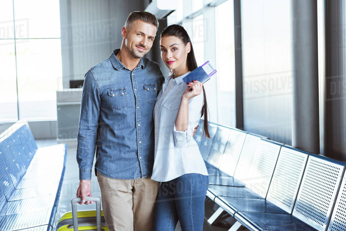 Happy couple standing in the airport and showing tickets - Royalty-free ...