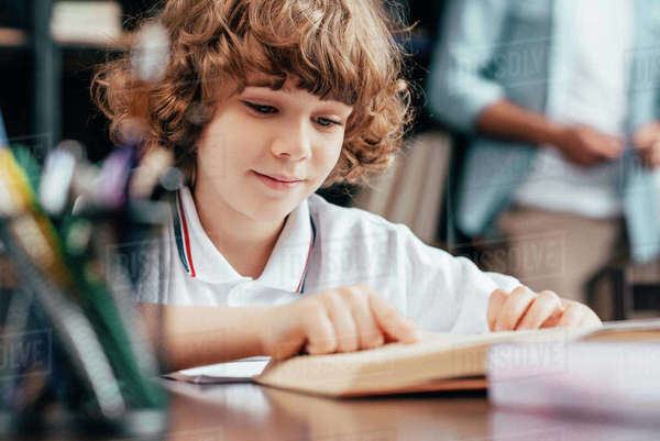 Smiling little boy reading old book for homework - Royalty-free Stock ...