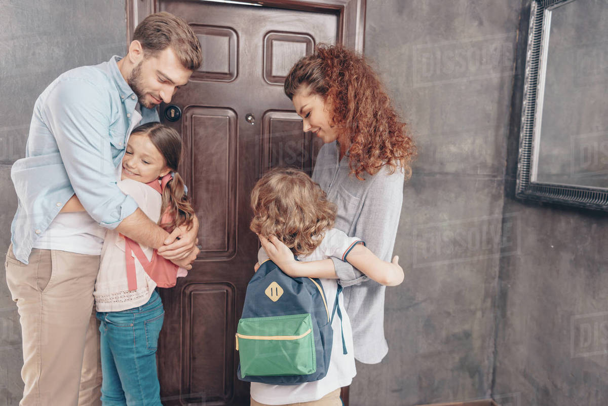 Cute parents hug kids before school - Stock Photo - Dissolve