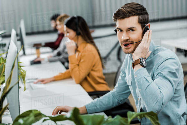 Selective focus of call center operator looking at camera while ...