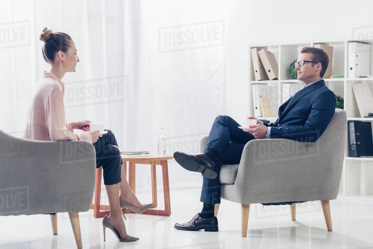 Side view of businessman giving interview to attractive journalist in ...