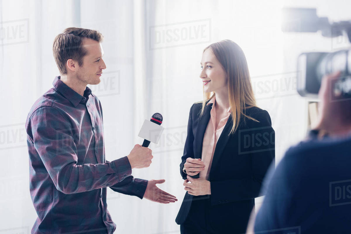Beautiful businesswoman in suit giving interview to handsome journalist ...