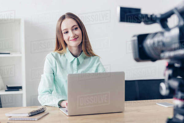 Cheerful attractive female video blogger recording vlog in office ...