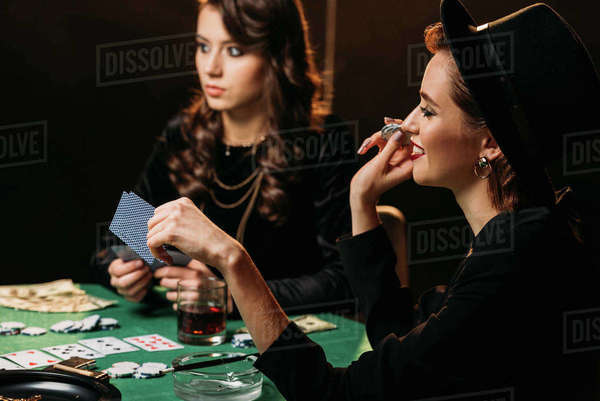 Attractive smiling girls playing poker at table in casino - Stock Photo ...